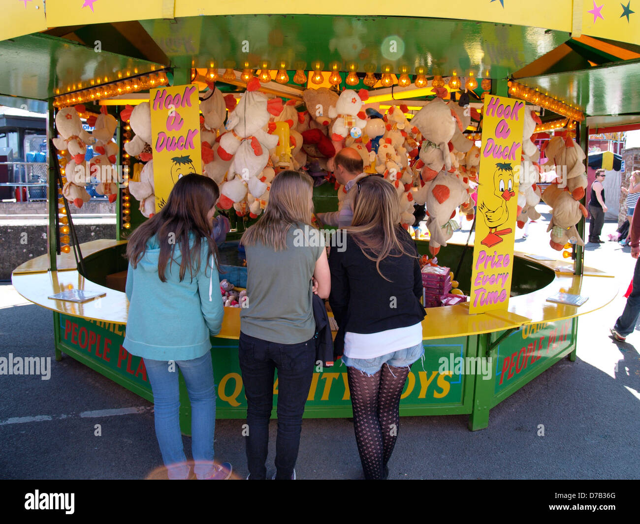 Three teenage girls at a hook a duck fairground stall, UK 2013 Stock ...