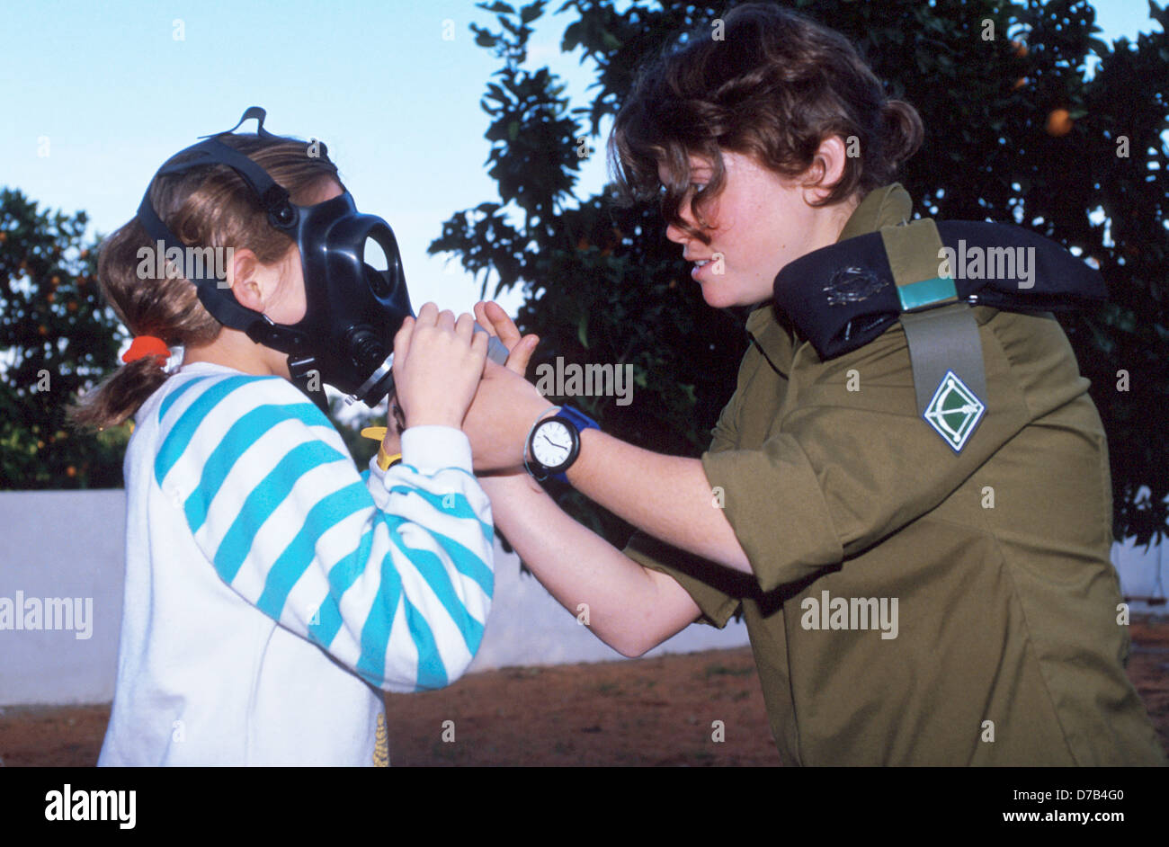 female soldier helps a child to wear a gas mask during the gulf war ...