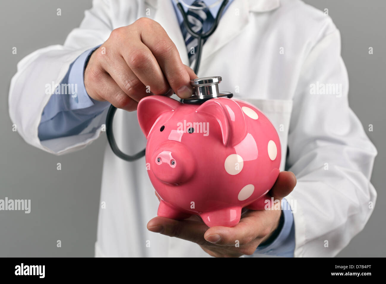 Doctor holding stethoscope to piggy bank Stock Photo - Alamy