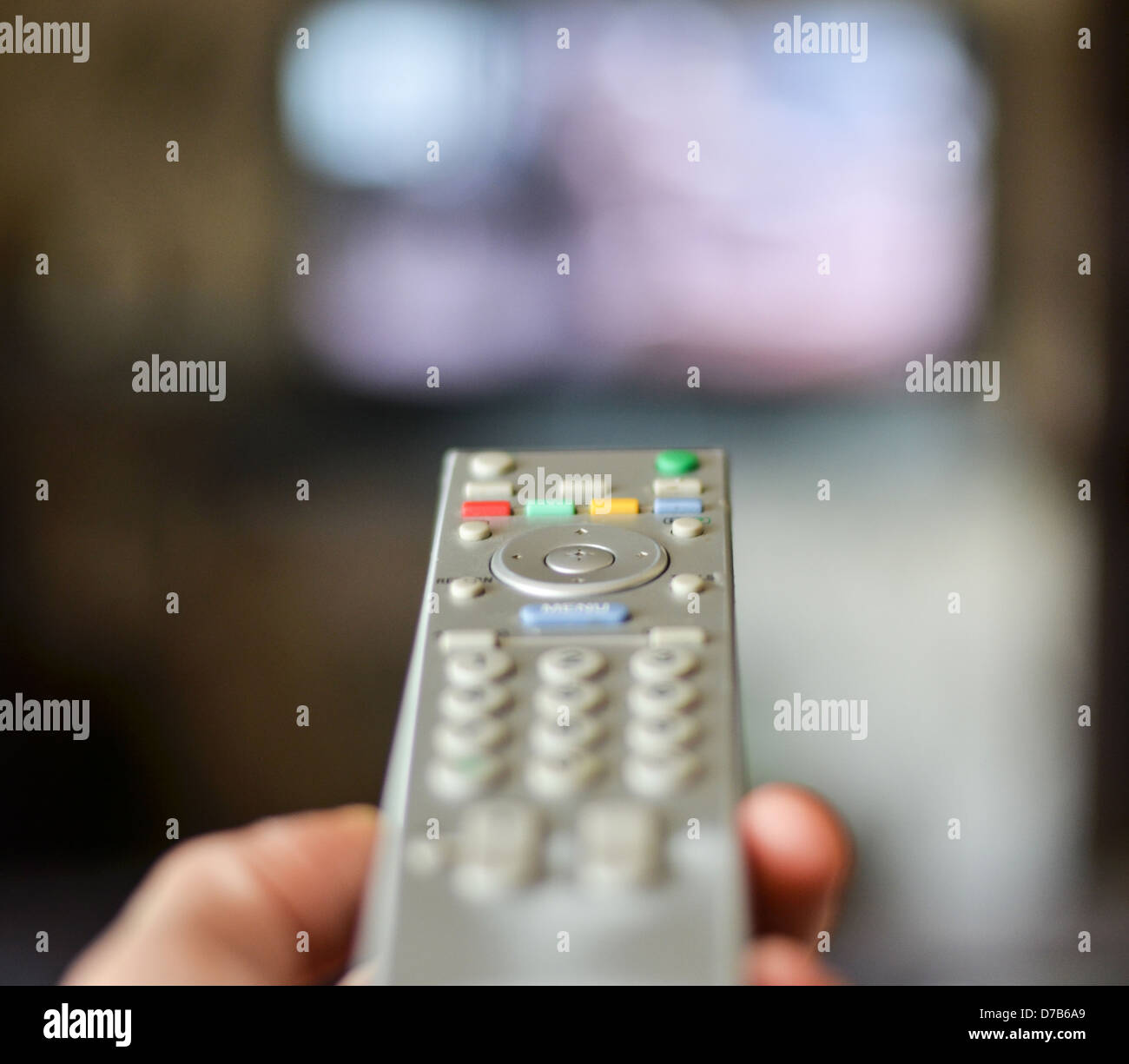 Hand holding remote controller with tv in the background Stock Photo ...