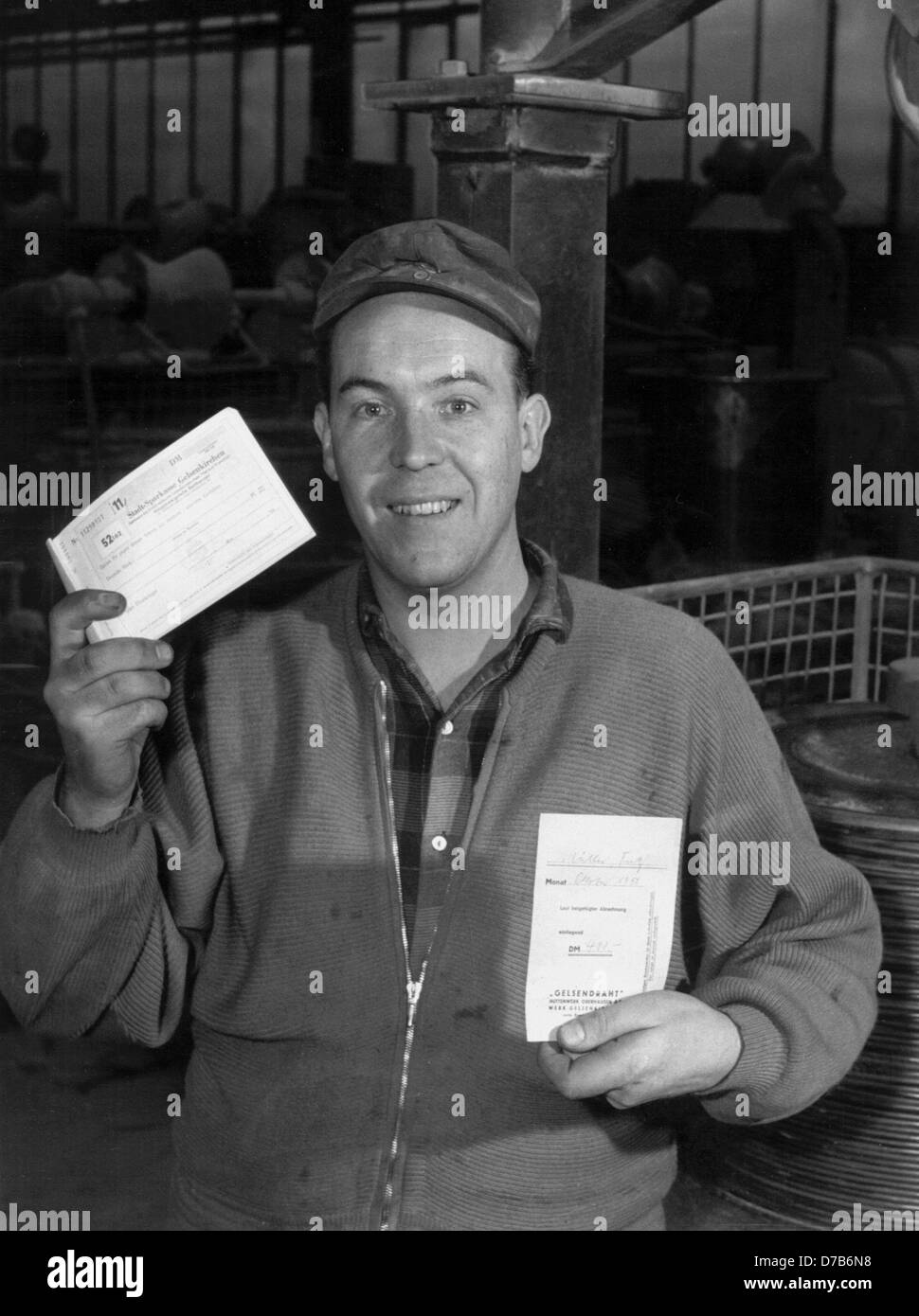A worker holds up a cheque which has replaced the traditional wage ...