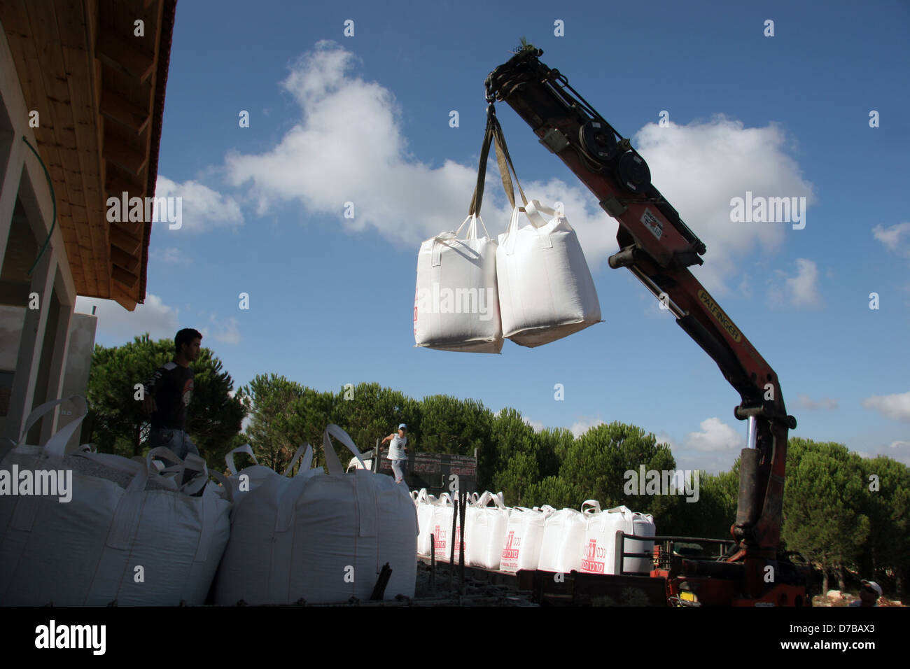 Crane lifting sacks with construction materials for building a house ...