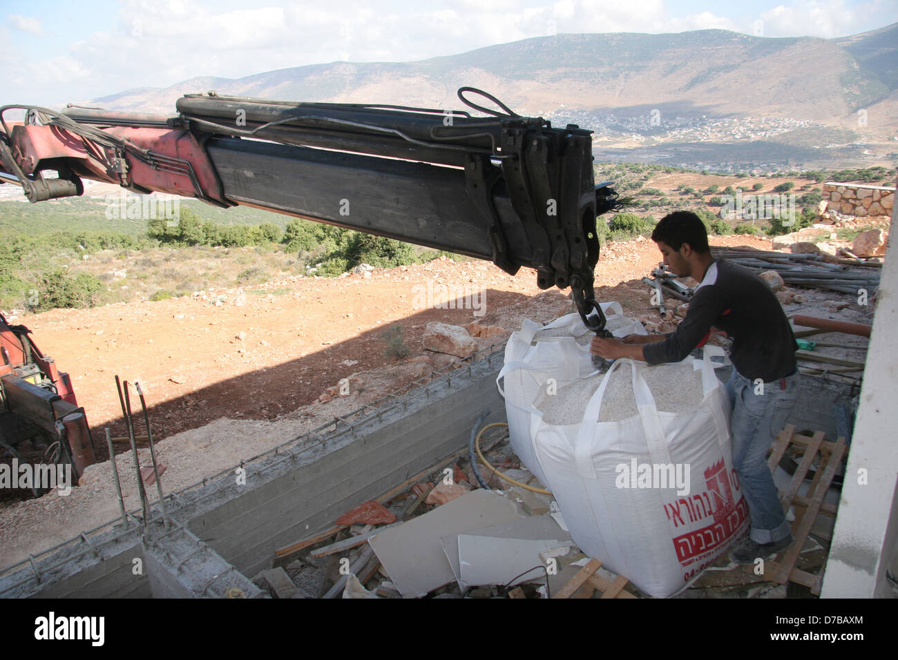 Crane lifting sacks with construction materials for building a house ...