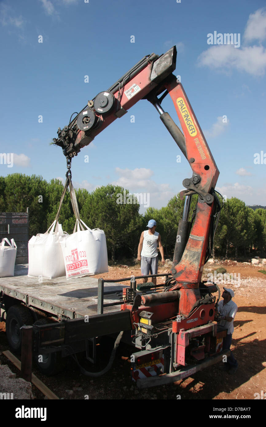 Crane lifting sacks with construction materials for building a house ...