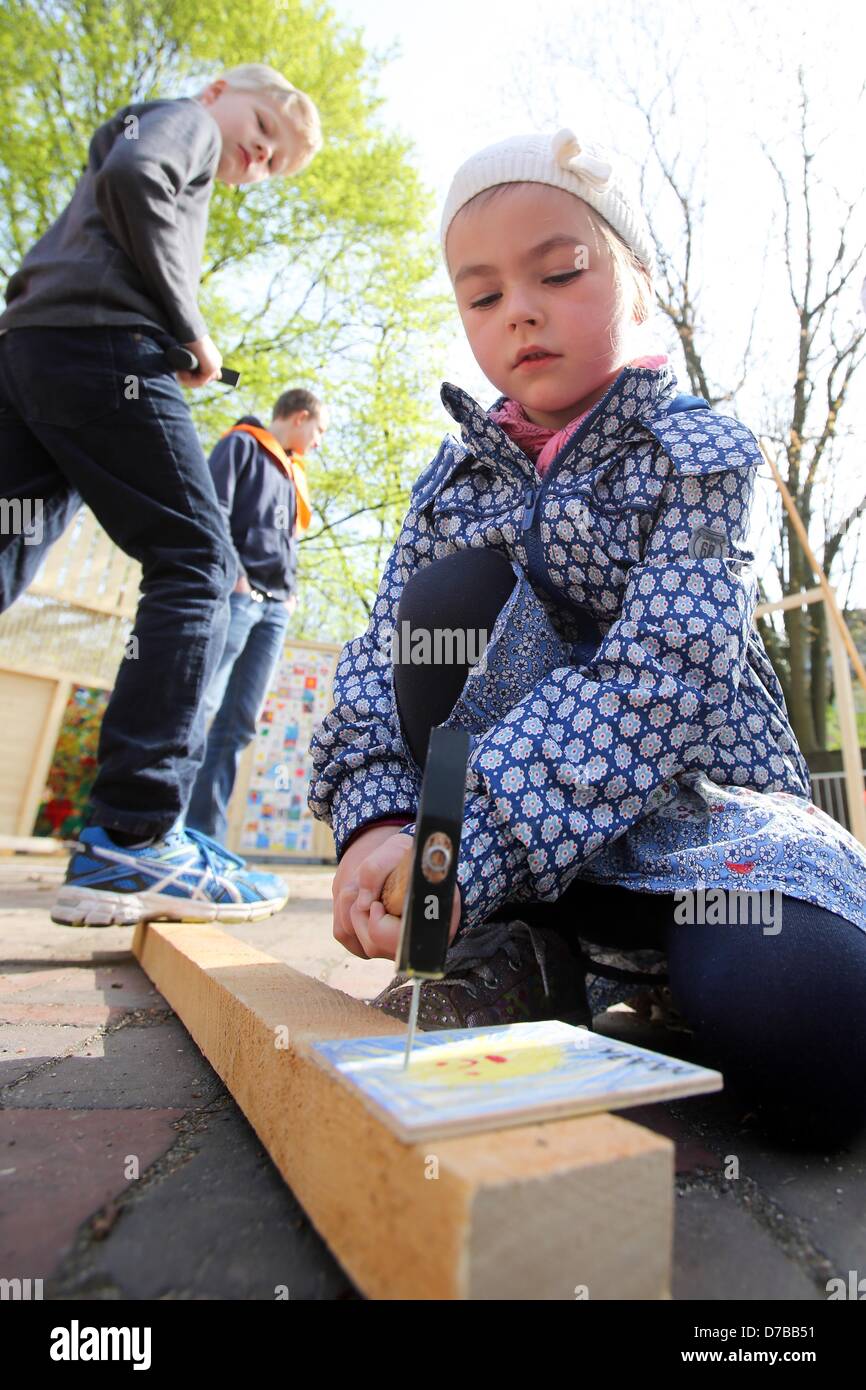 Five-year-old Maya hammers nails into a piece of wood covered with ...