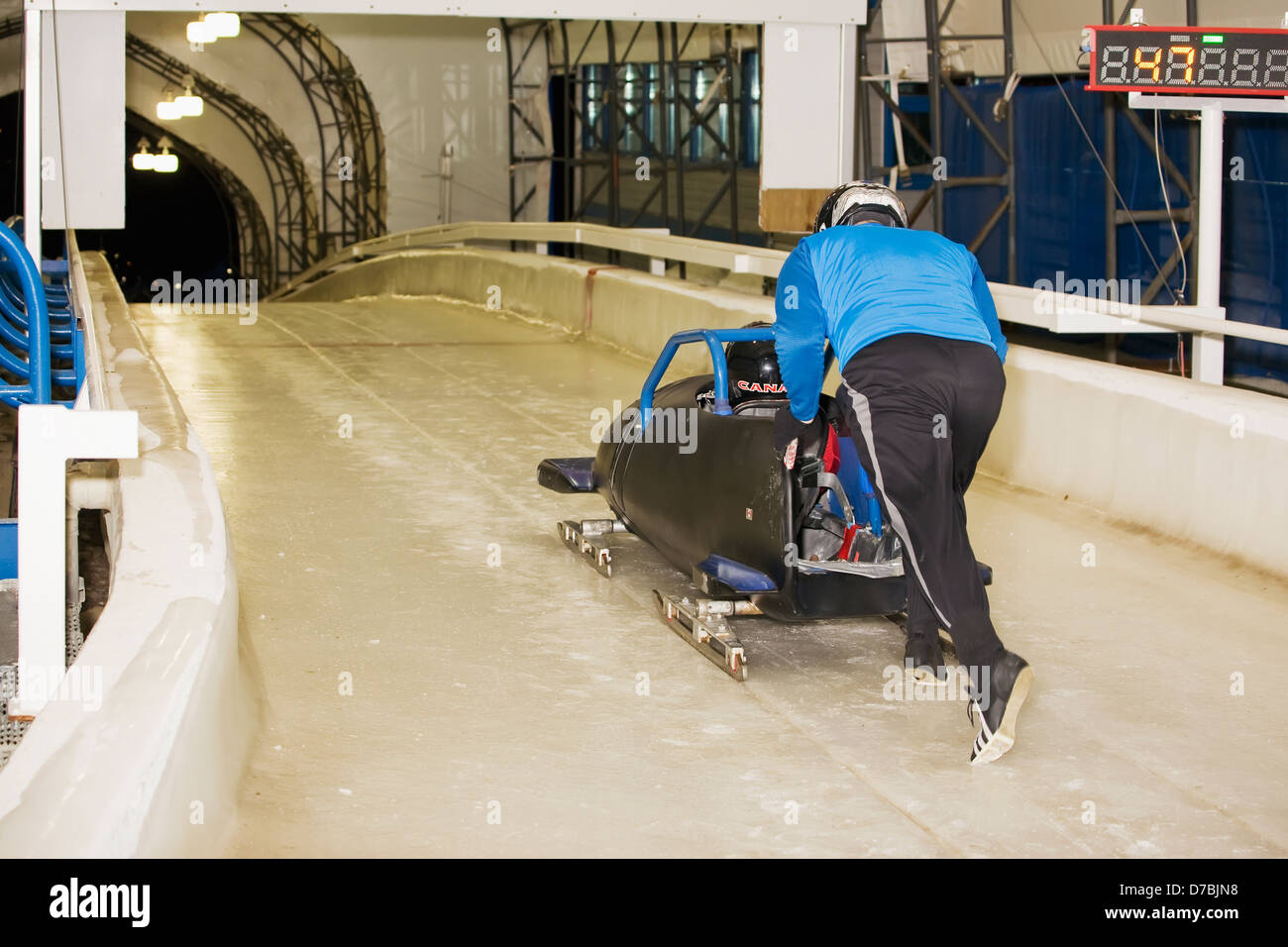 Bobsled runner running at the start with wheelchair athlete;Calgary ...