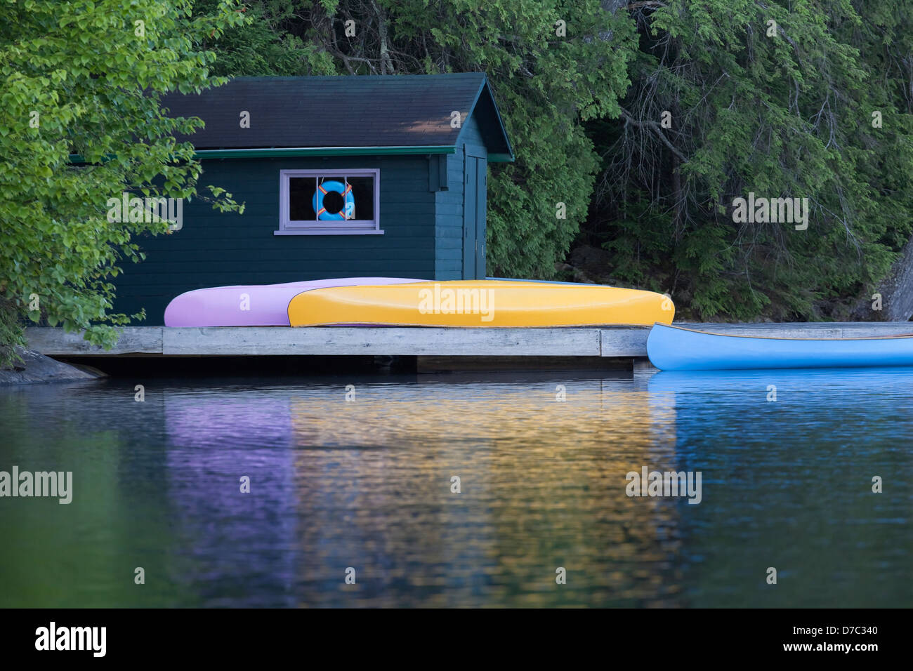 Colorful Canoes On A Cottage Dock And Reflected In The Water At ...