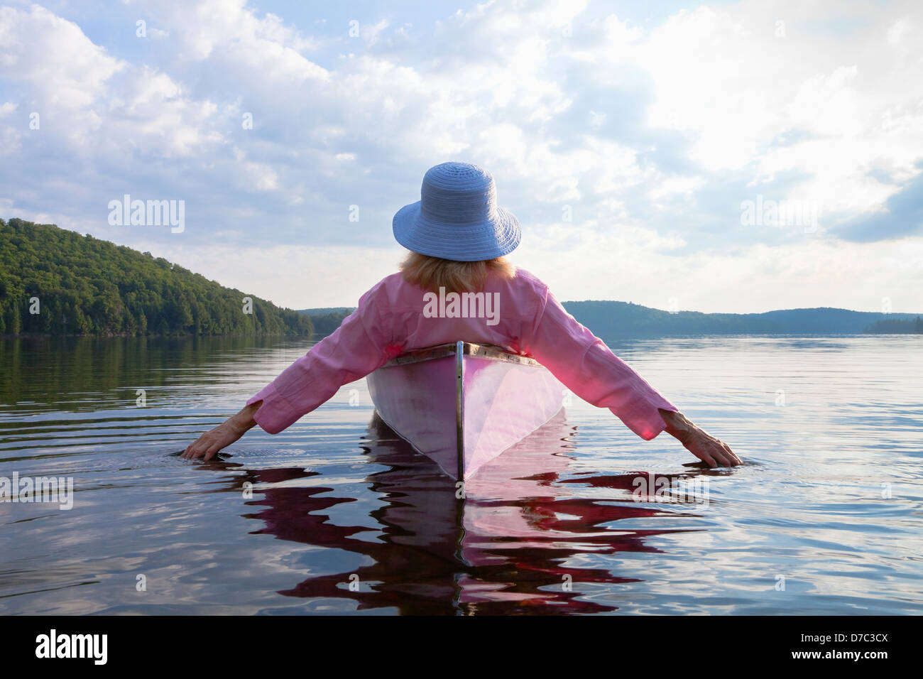 Senior Woman Dressed In Pink And Trailing Her Hands In The Water From ...