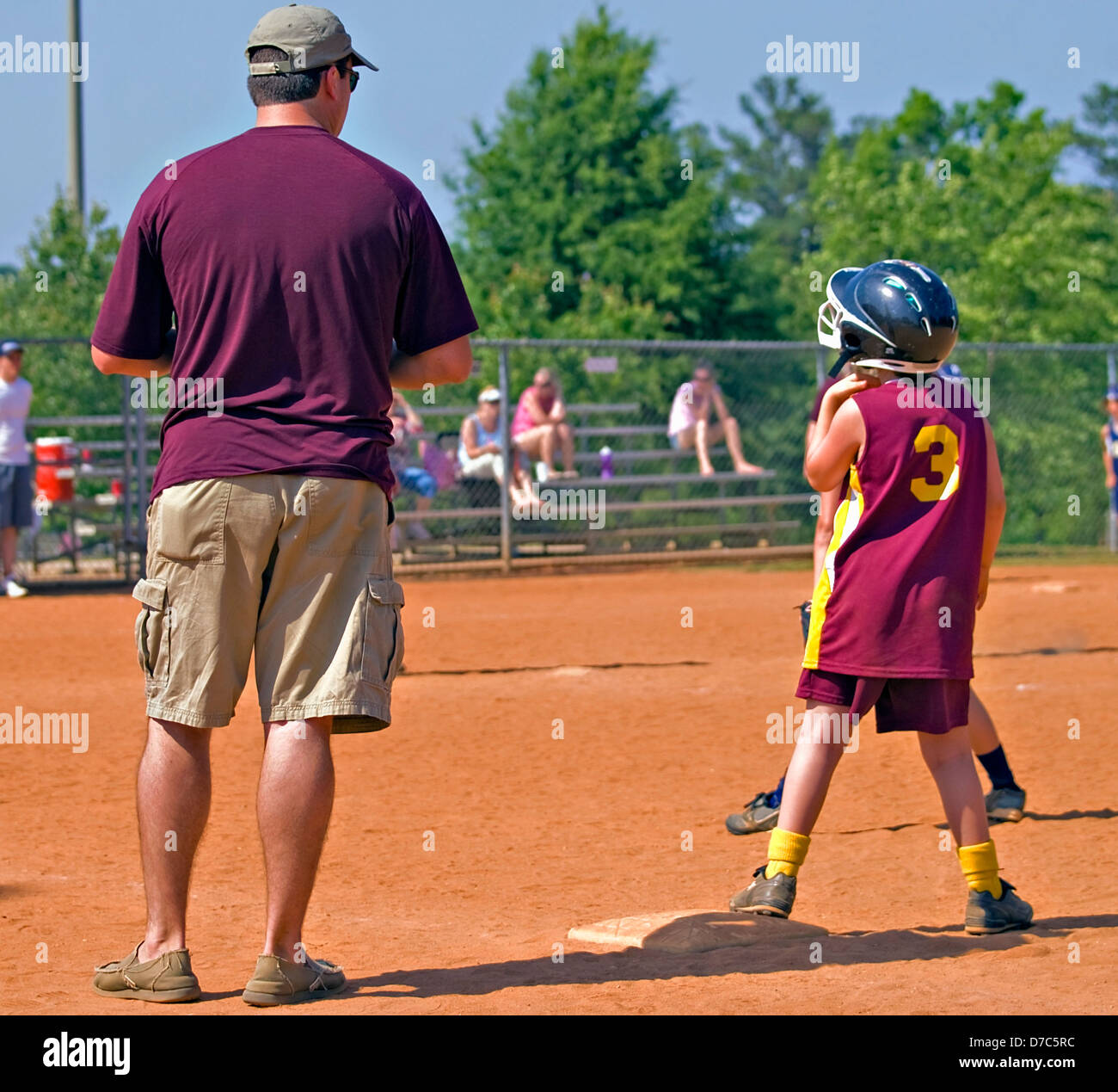 A man standing with his daughter during a softball game giving ...