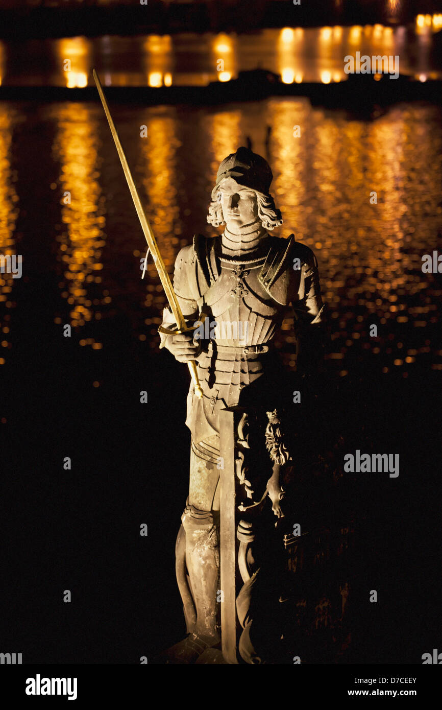 Statue illuminated by light with light reflecting on the water in the ...