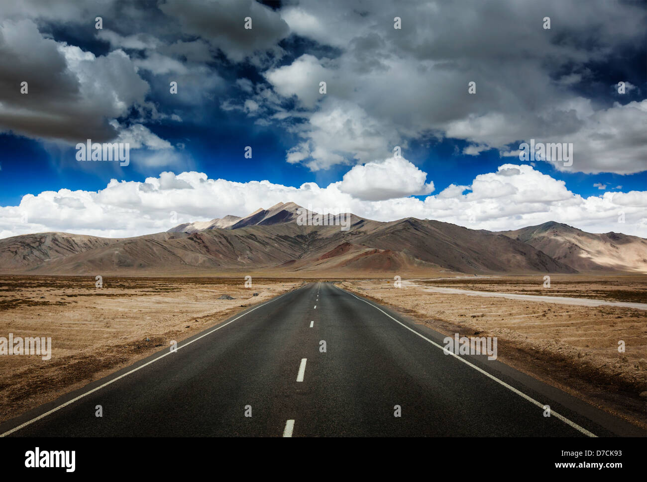 Travel forward concept background - road on plains in Himalayas with mountains and dramatic ...