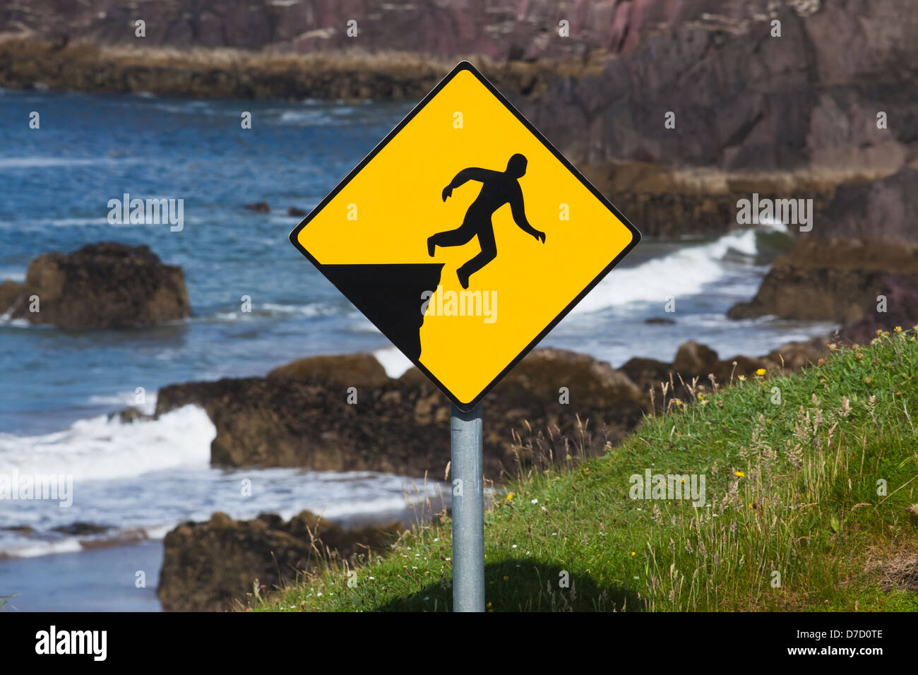 A yellow warning sign depicting a person falling off a cliff;County ...