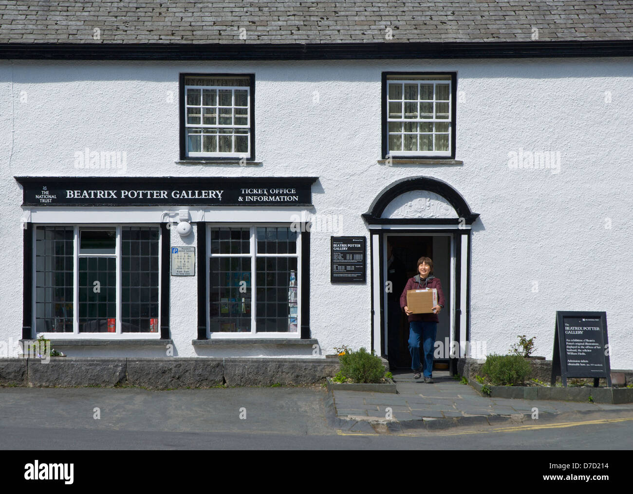 Young Asian woman carrying box out of Beatrix Potter Gallery, Hawkshead ...