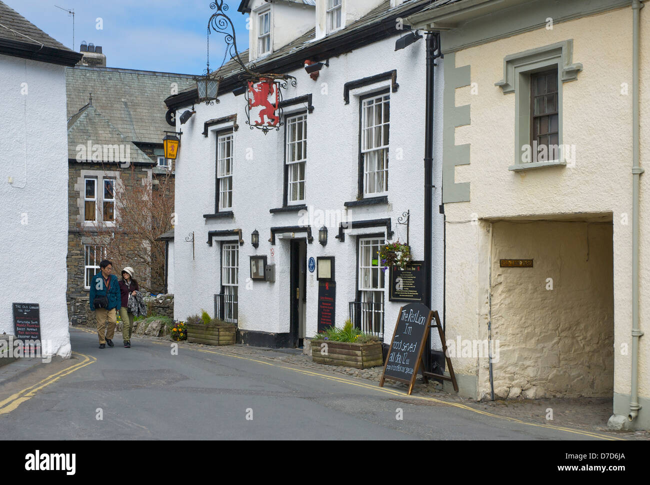 Young Asian couple walking past the Red Lion Inn, in Hawkshead, Lake ...