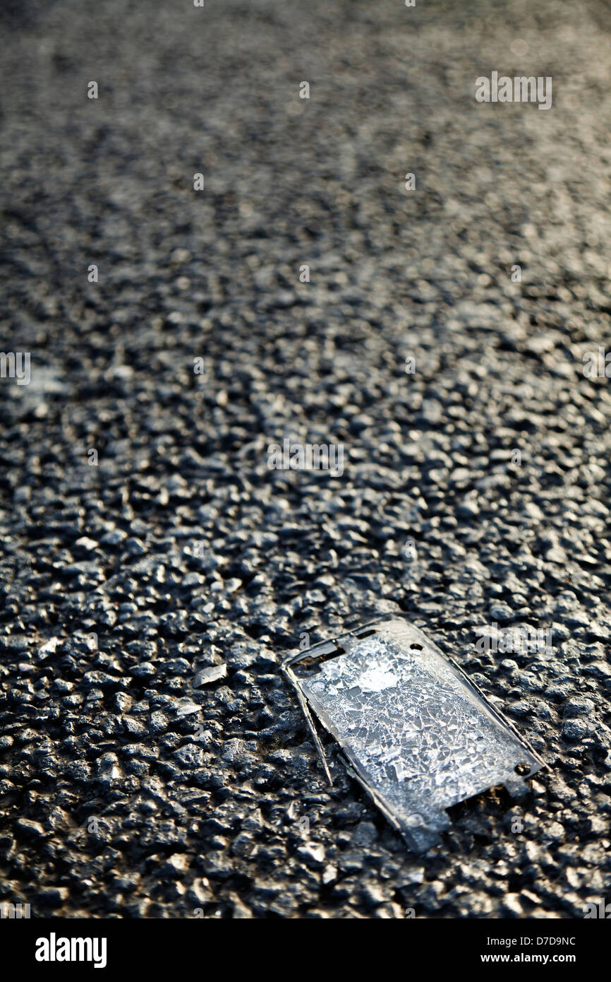 Close up of a shattered plastic cellphone panel laying on asphalt road ...