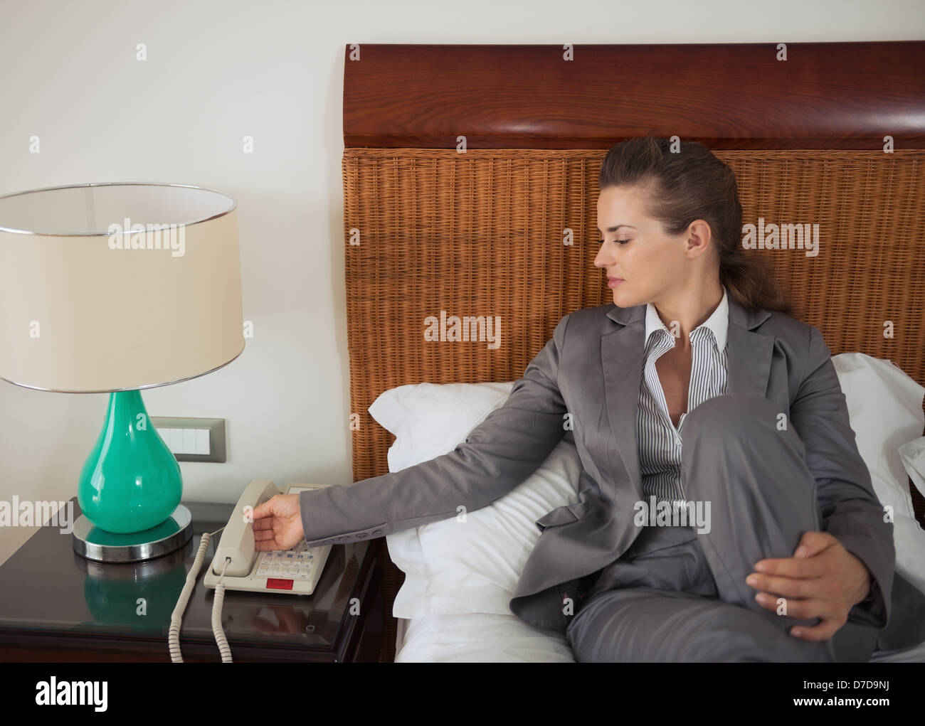 Business woman answering phone call on bed in hotel room Stock Photo ...