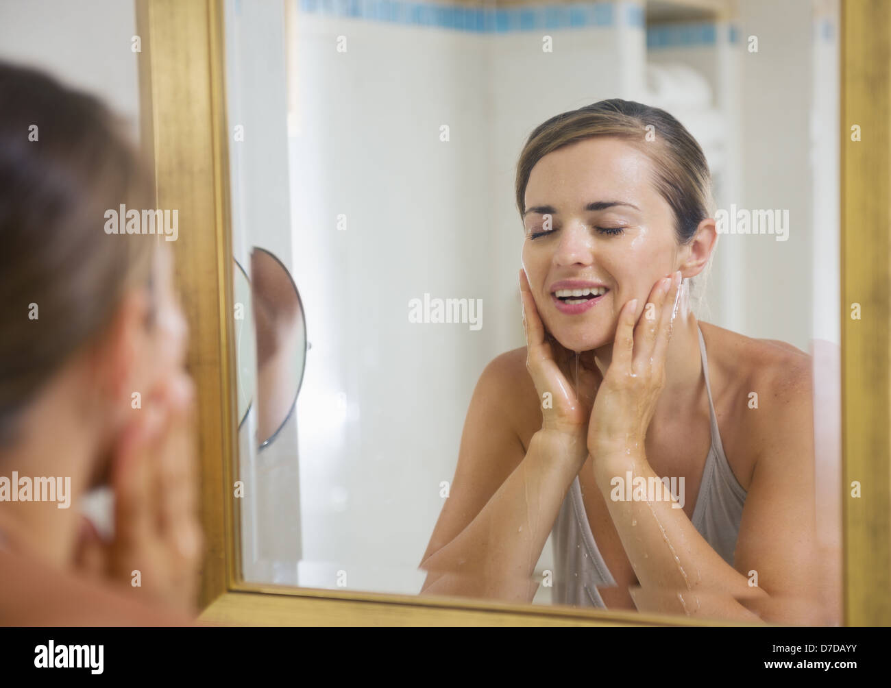 Happy young woman washing face in bathroom Stock Photo - Alamy