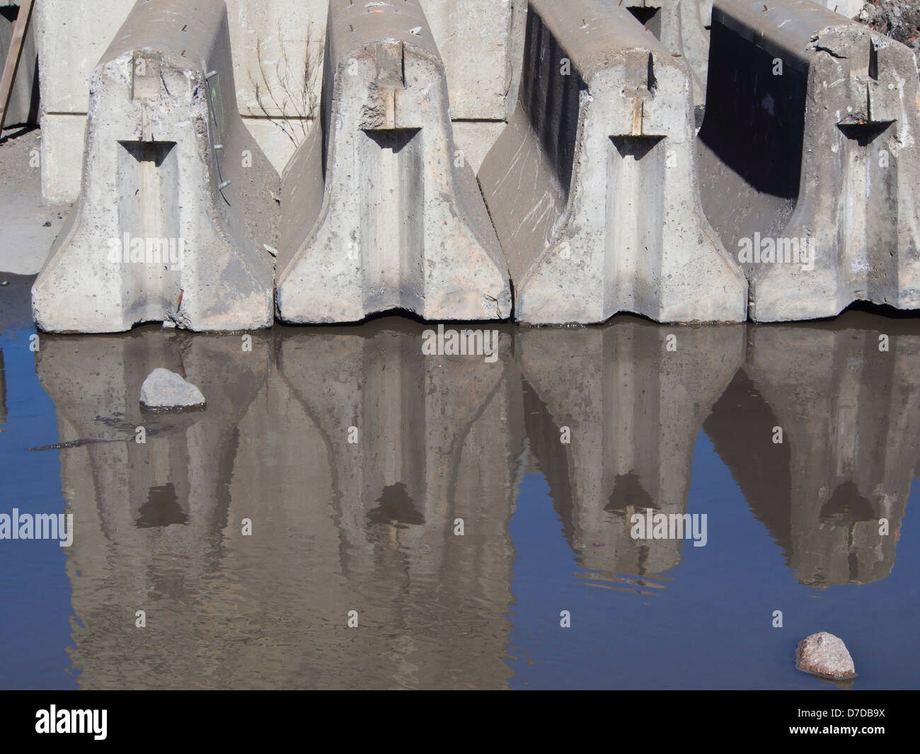 concrete construction blocks, y shaped, reflected in a puddle of water ...