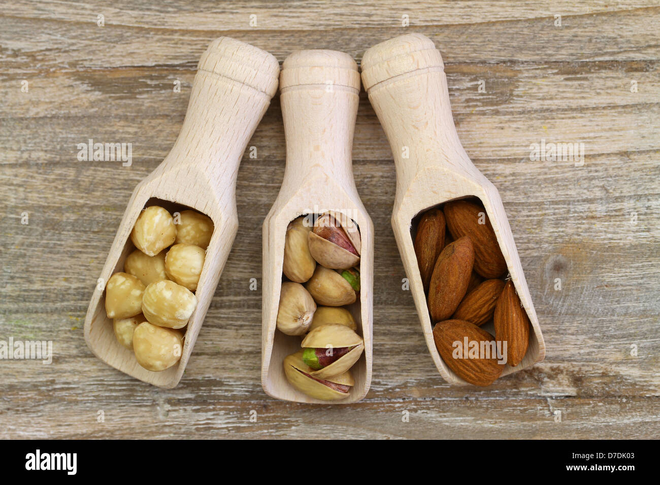 Pistachio nuts, almonds and hazelnuts on wooden scoops, close up Stock ...