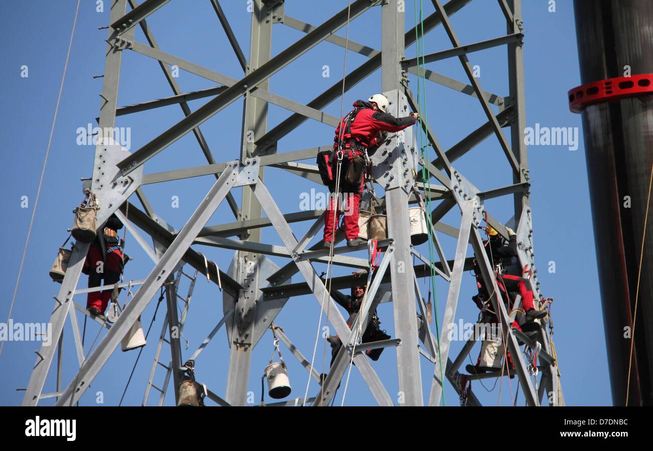 Workers prepare a lattice tower to hang power lines in Buettel, Germany ...