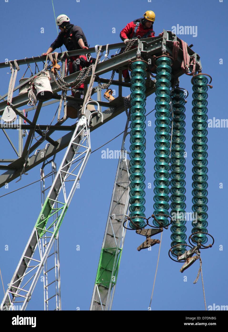 Workers prepare a lattice tower to hang power lines in Buettel, Germany ...