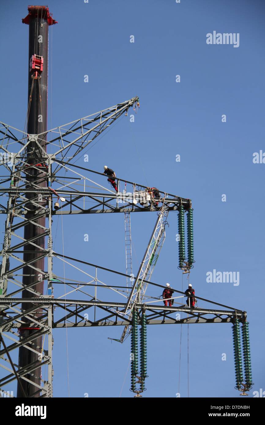 Workers prepare a lattice tower to hang power lines in Buettel, Germany ...