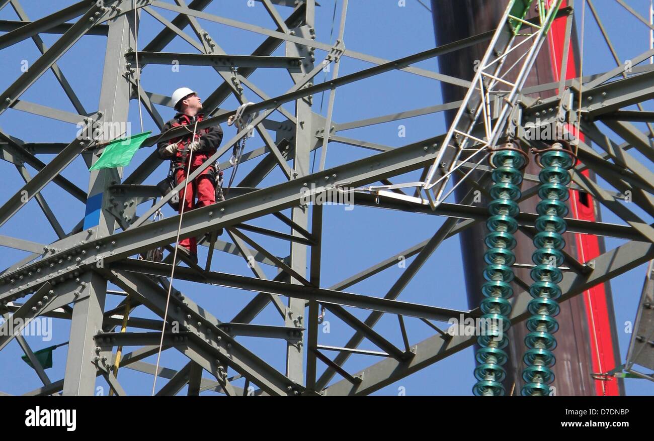Workers prepare a lattice tower to hang power lines in Buettel, Germany ...