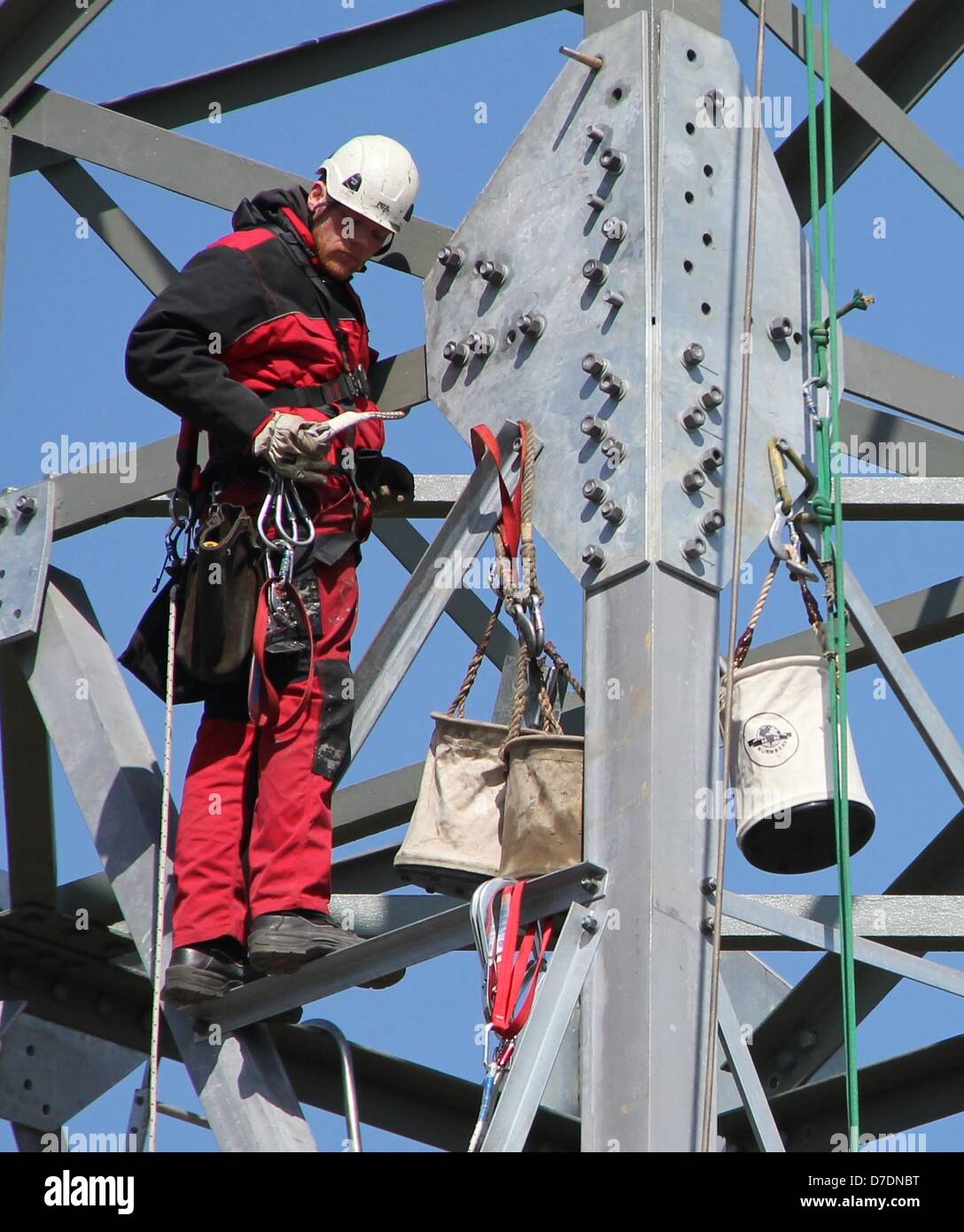 Workers prepare a lattice tower to hang power lines in Buettel, Germany ...