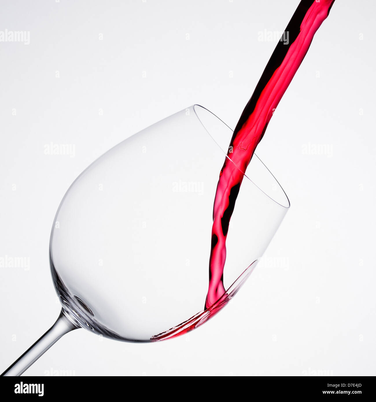 Wine pouring into a glass in diagonal composition and white background ...