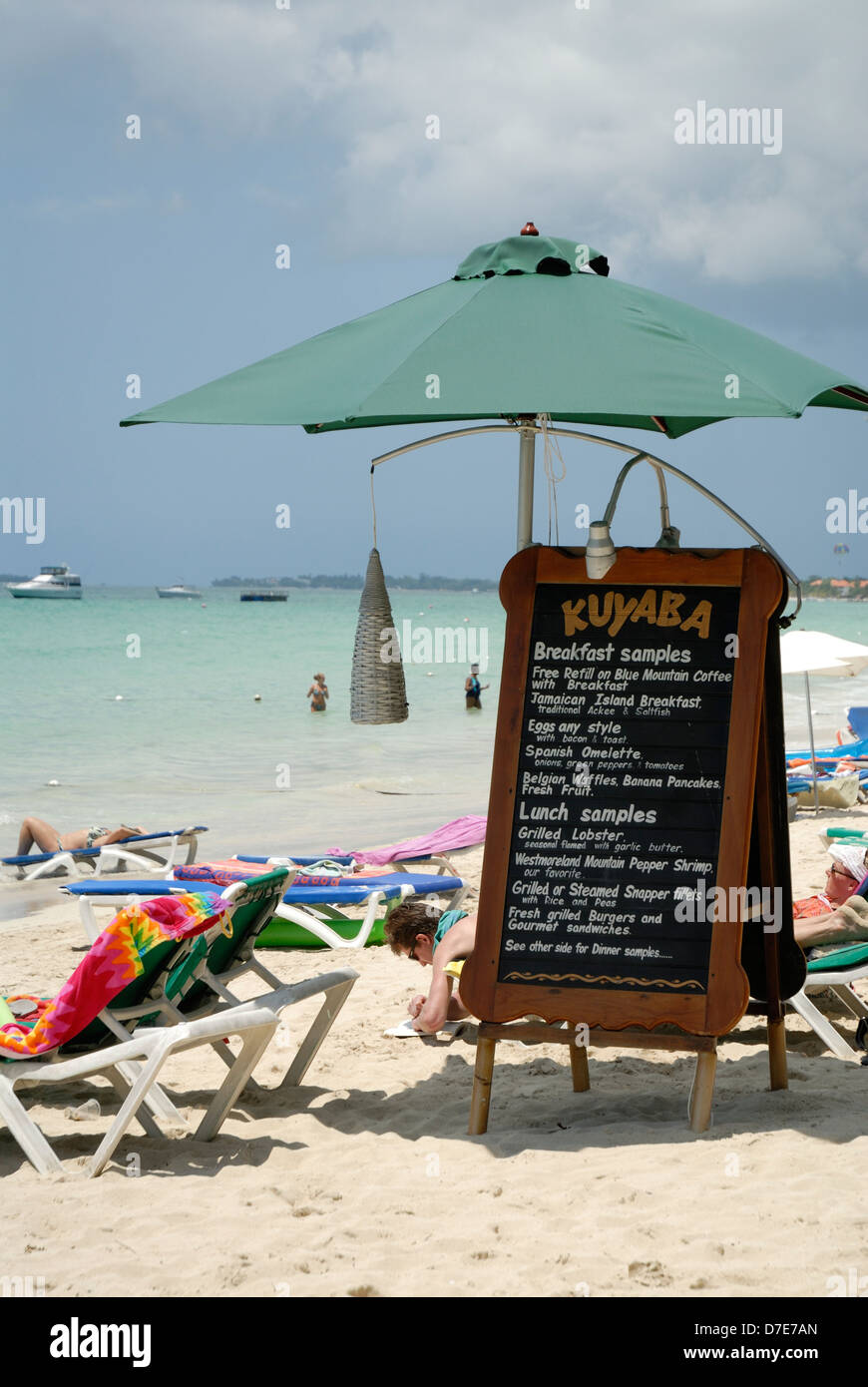 Kuyaba Menu Sign and Sunbathers on 7-Mile Beach Stock Photo - Alamy