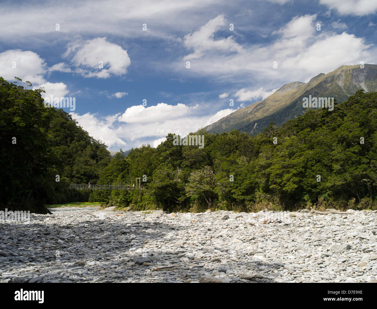 Tourists cross the Makarora River on a suspension bridge, Mount ...