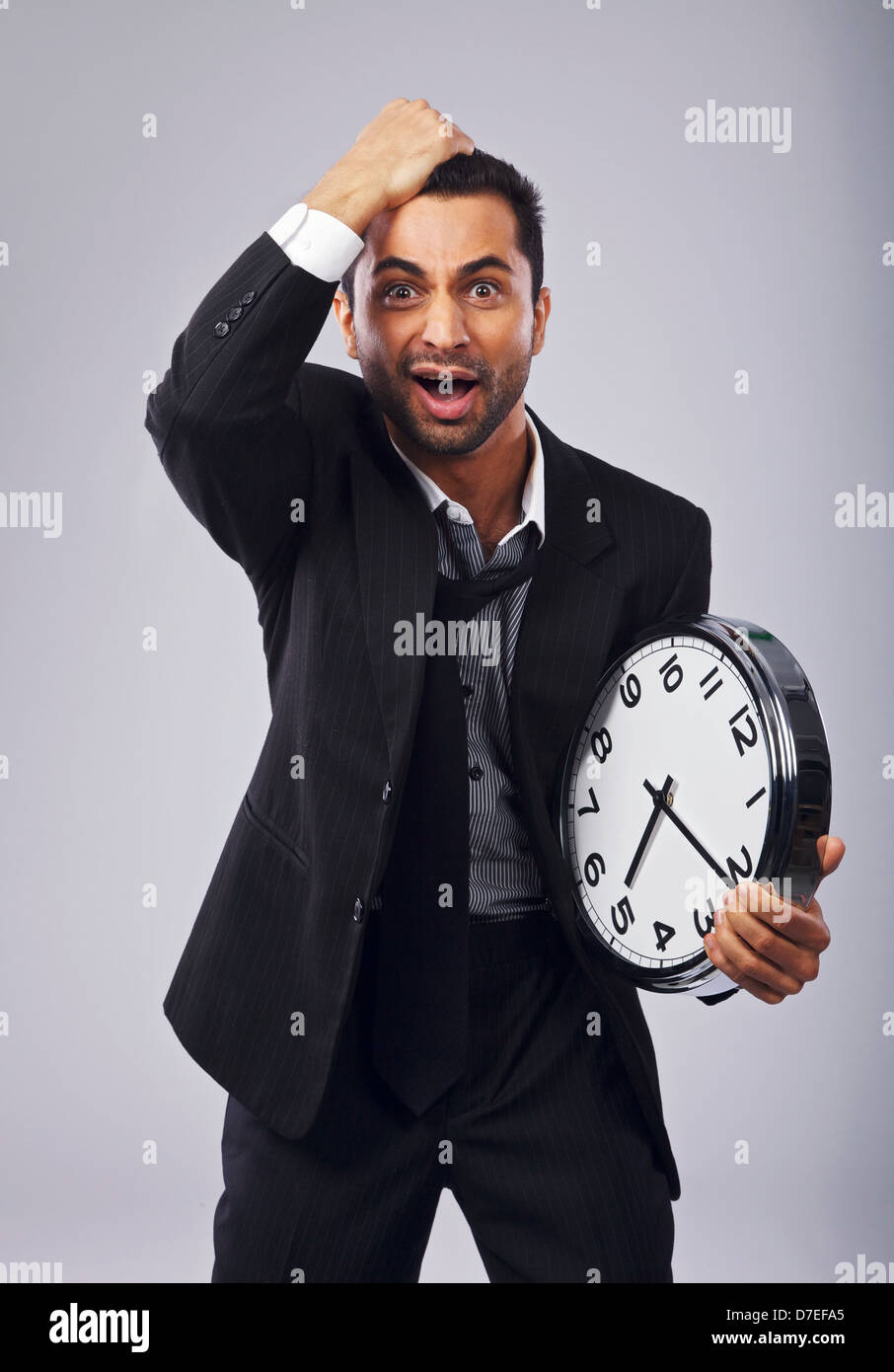 Frustrated businessman holding a clock Stock Photo - Alamy