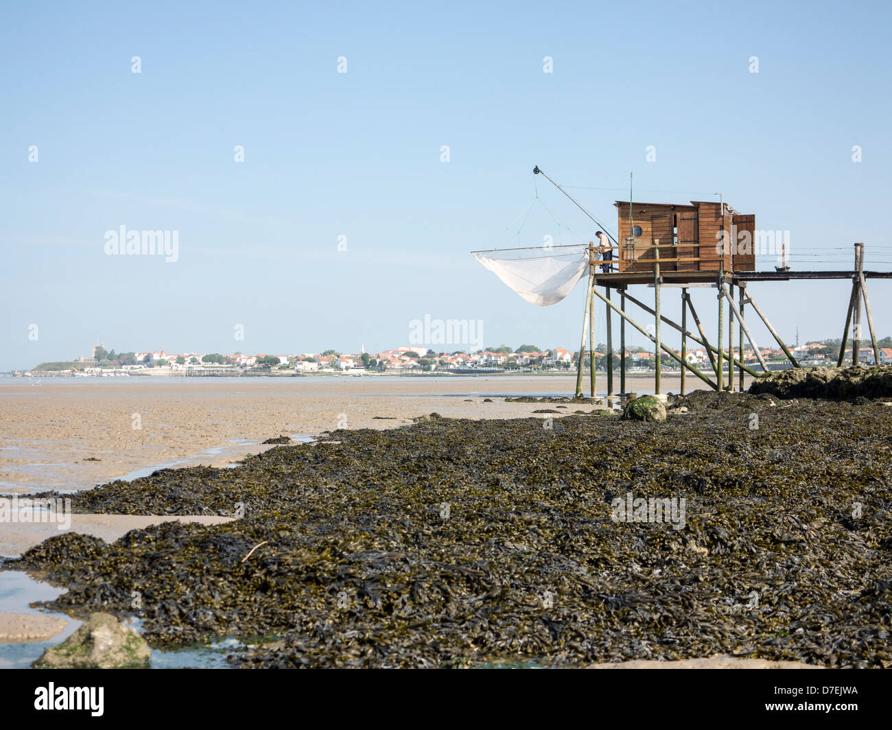 A fisherman repairs his net in a Carrelet fishing hut on stilts on the ...