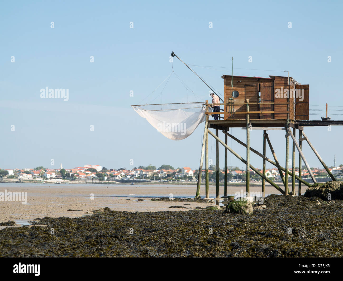A fisherman repairs his net in a Carrelet fishing hut on stilts on the ...