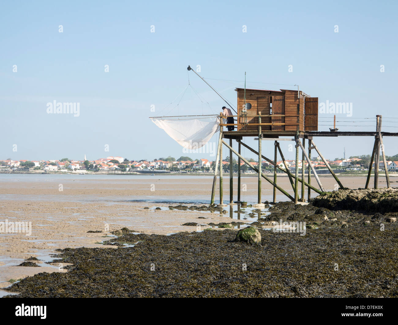 A fisherman repairs his net in a Carrelet fishing hut on stilts on the ...