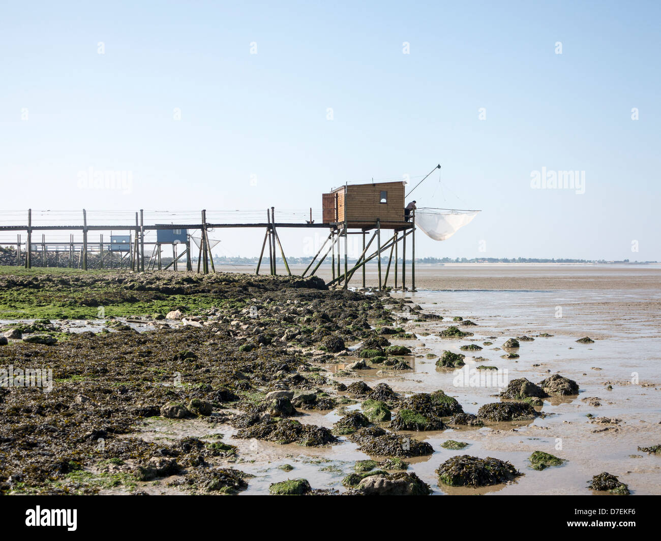 A fisherman repairs his net in a Carrelet fishing hut on stilts on the ...