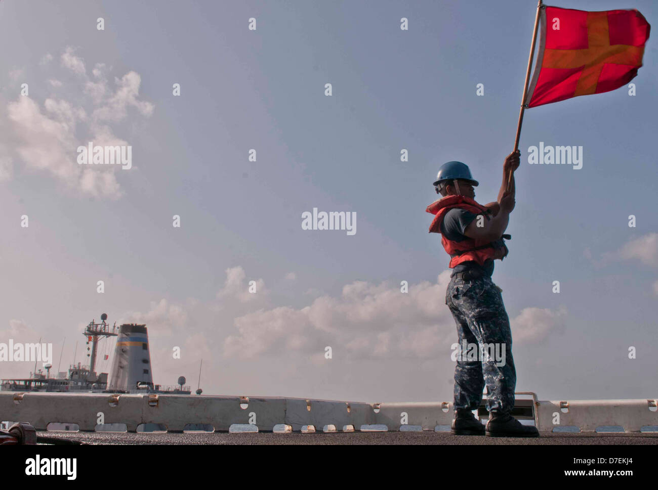 A Sailor waves the Romeo flag during a replenishment-at-sea Stock Photo ...