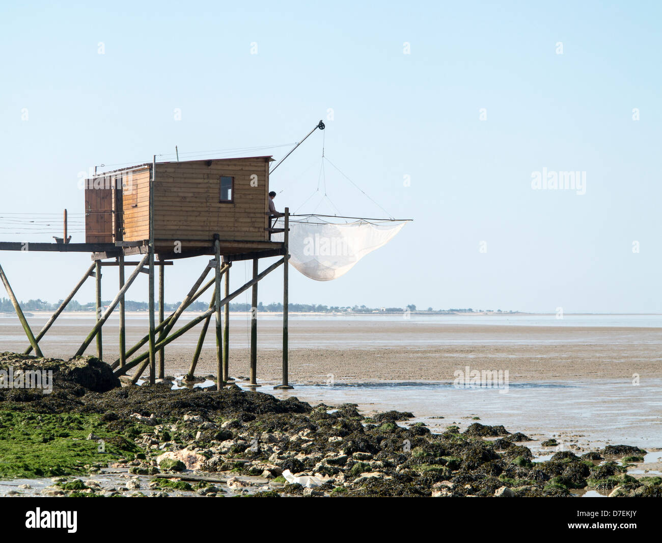 A fisherman repairs his net in a Carrelet fishing hut on stilts on the ...