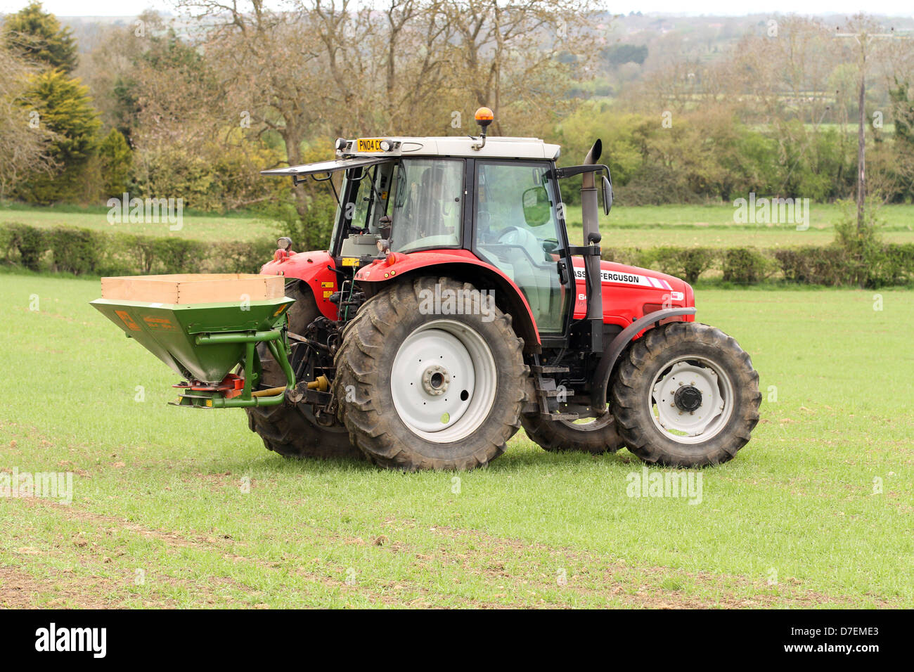 Farmer worker driving a big red tractor to spread chemical fertilizer ...