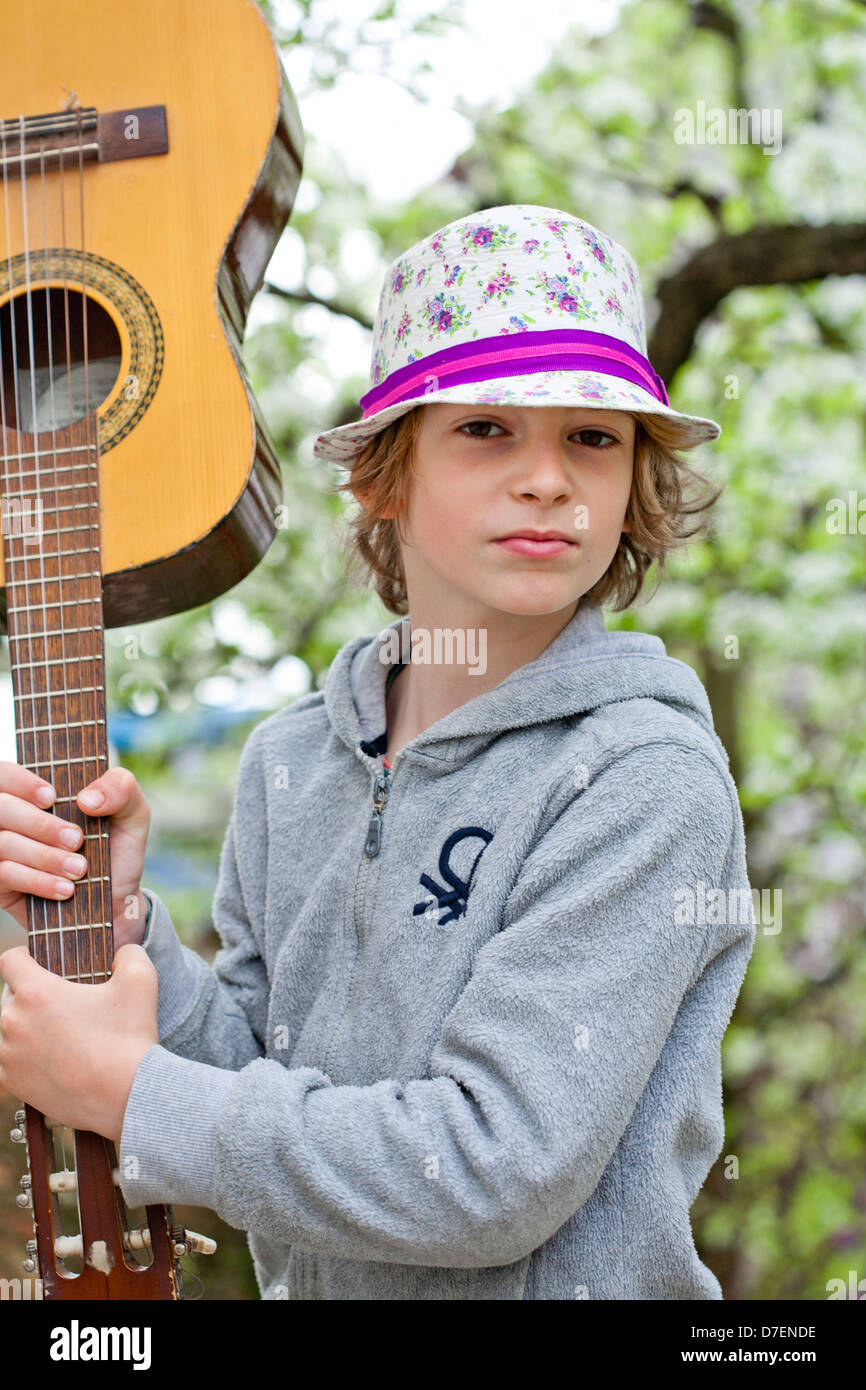 Portrait of a Boy playing an acoustic guitar outdoor in the garden ...