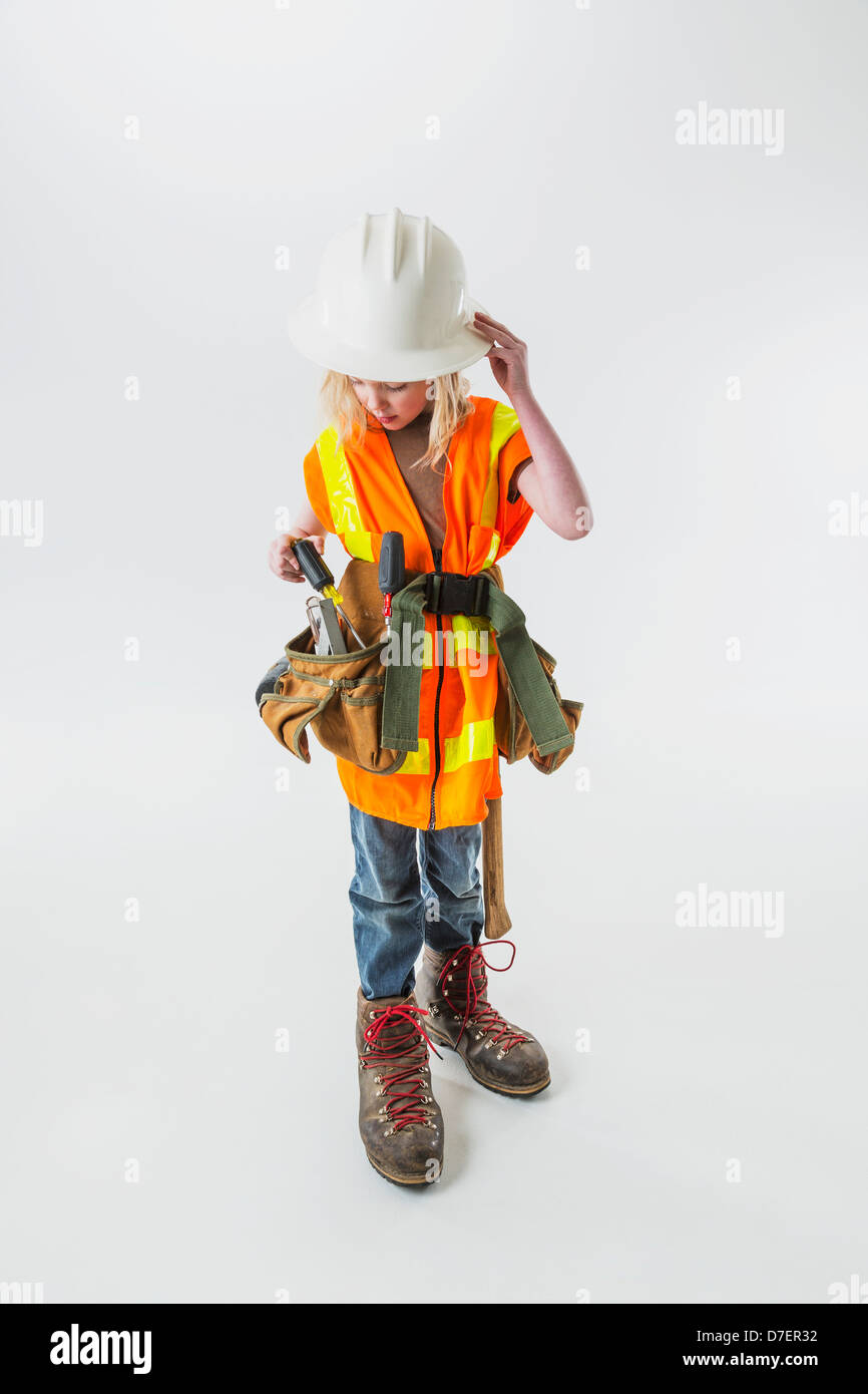 Young girl wearing oversized construction clothes and hard hat pulling ...