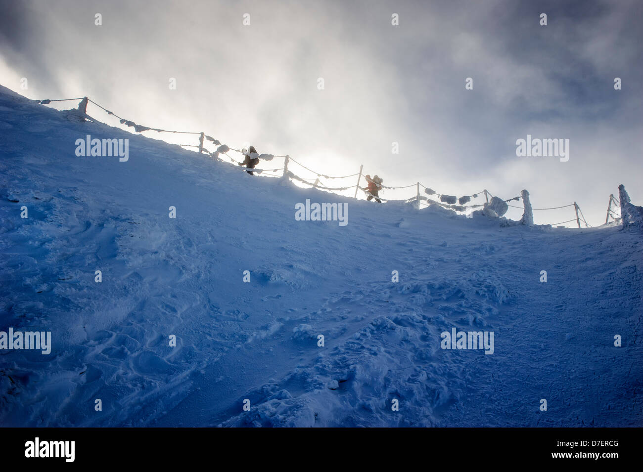 Hikers climbing a frozen side of a mountain, Karkonosze mountains ...