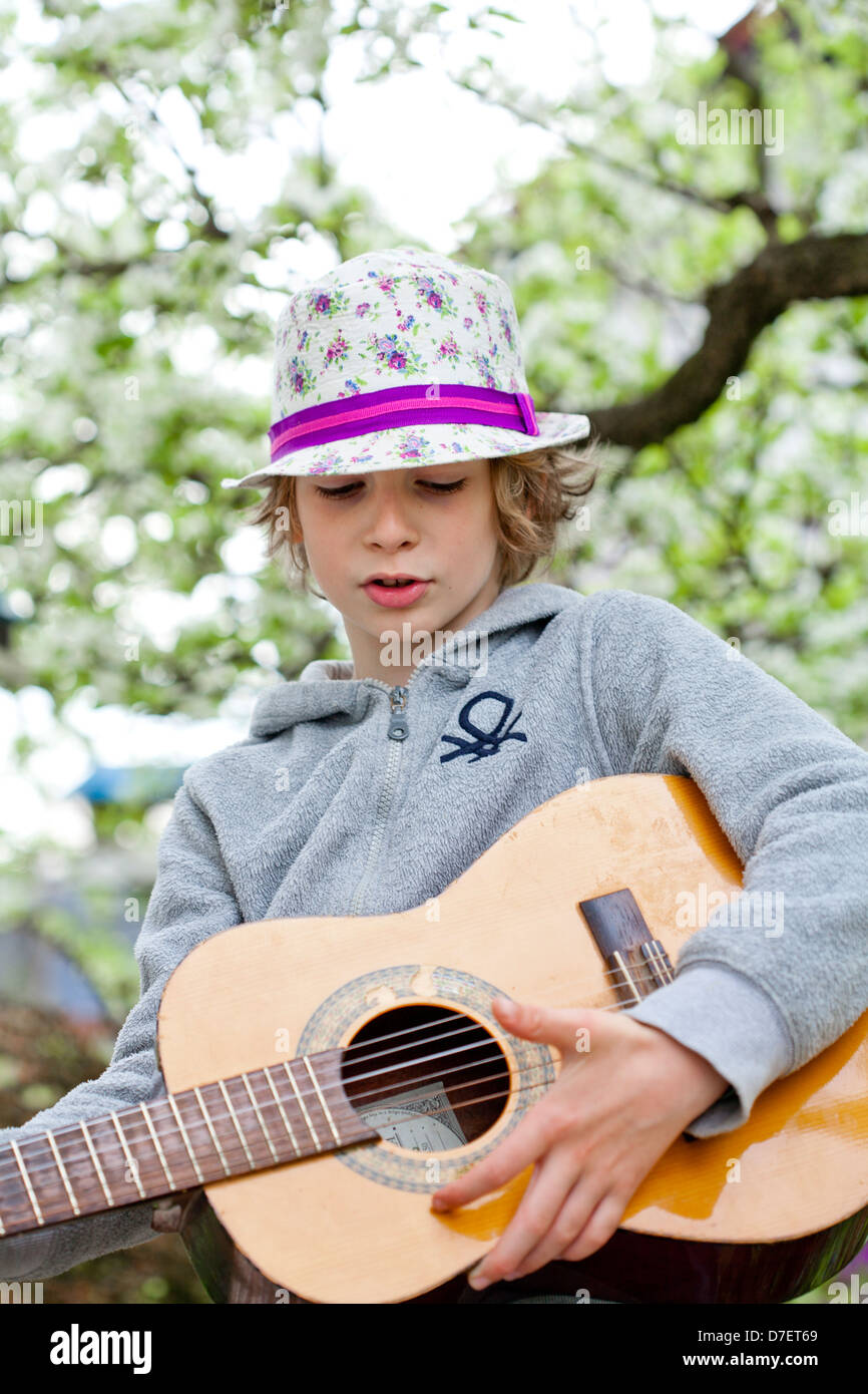 Portrait of a Boy playing an acoustic guitar outdoor in the garden ...