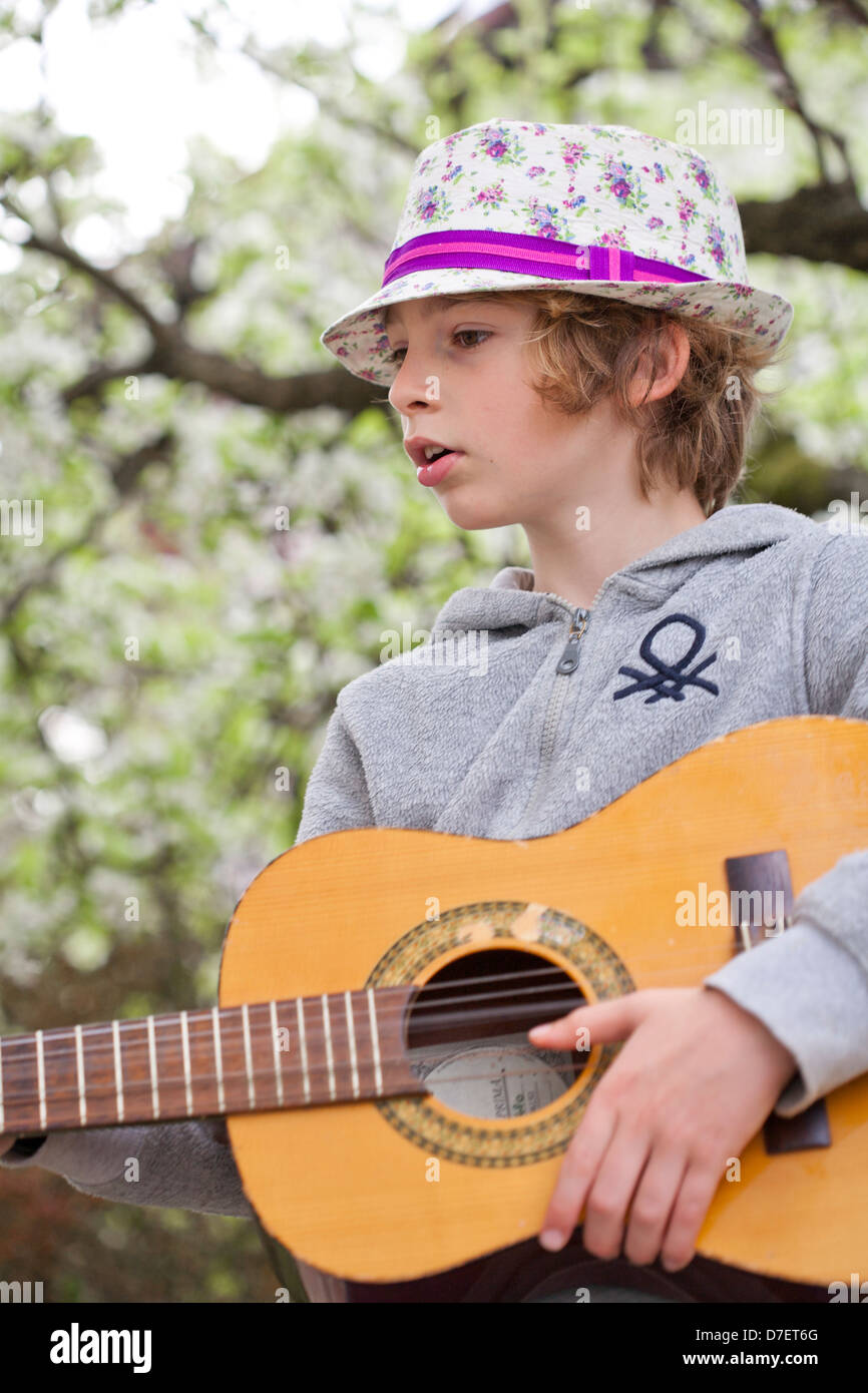 Portrait of a Boy playing an acoustic guitar outdoor in the garden ...