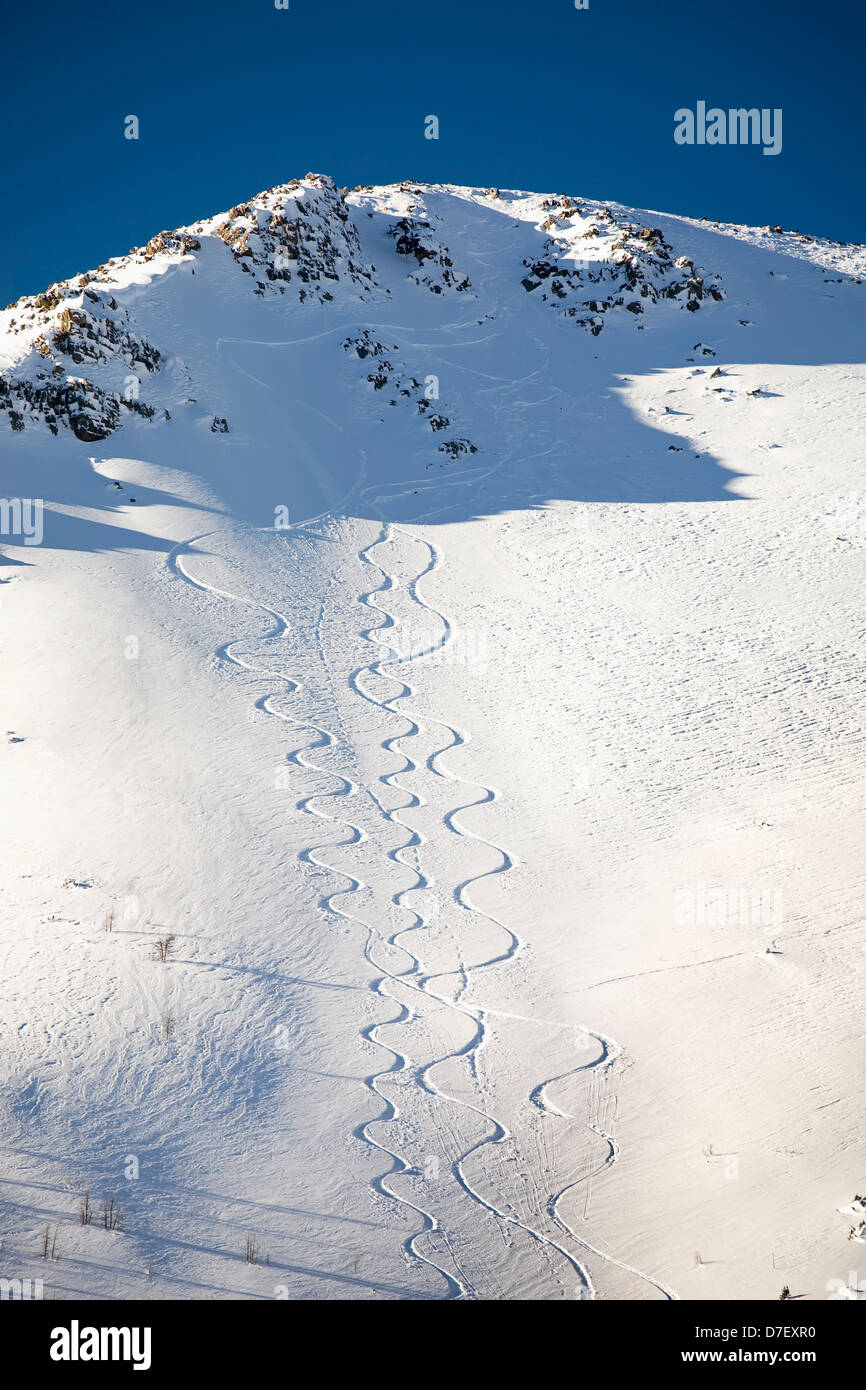 Snow covered mountain peak with skier tracks and deep blue sky;Lake ...