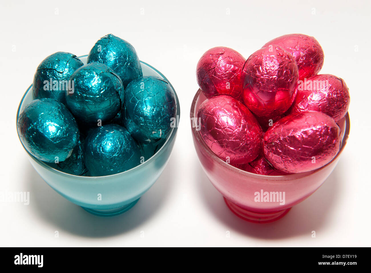 Orange, blue and pink chocolate Easter eggs in glass cups of the same ...