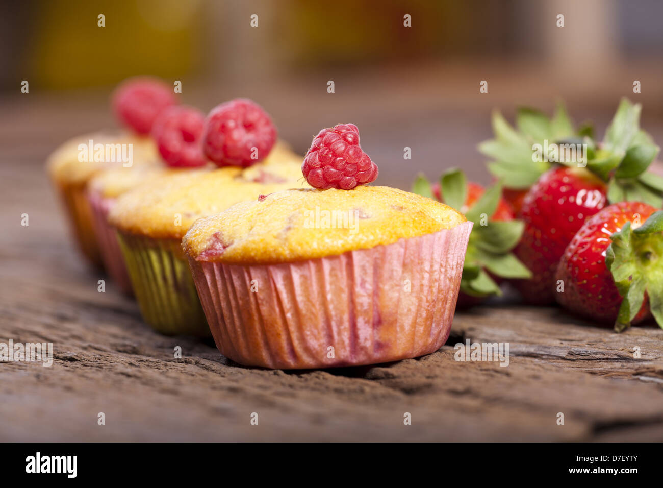 Four whole tasty fruit muffins with a raspberry on the top in a row on ...