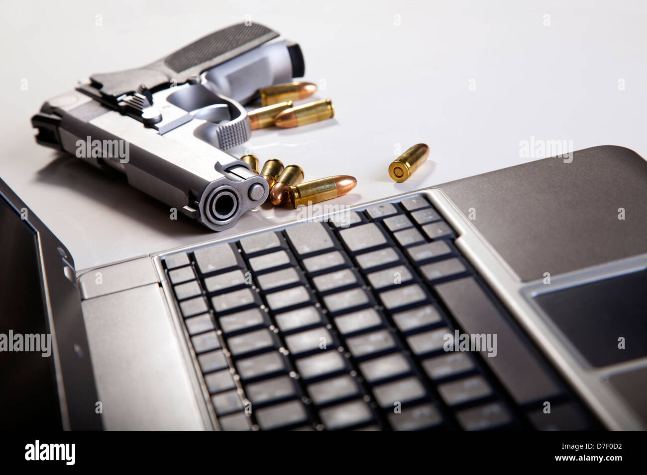A 9mm handgun with scattered bullets beside it and part of a laptop ...