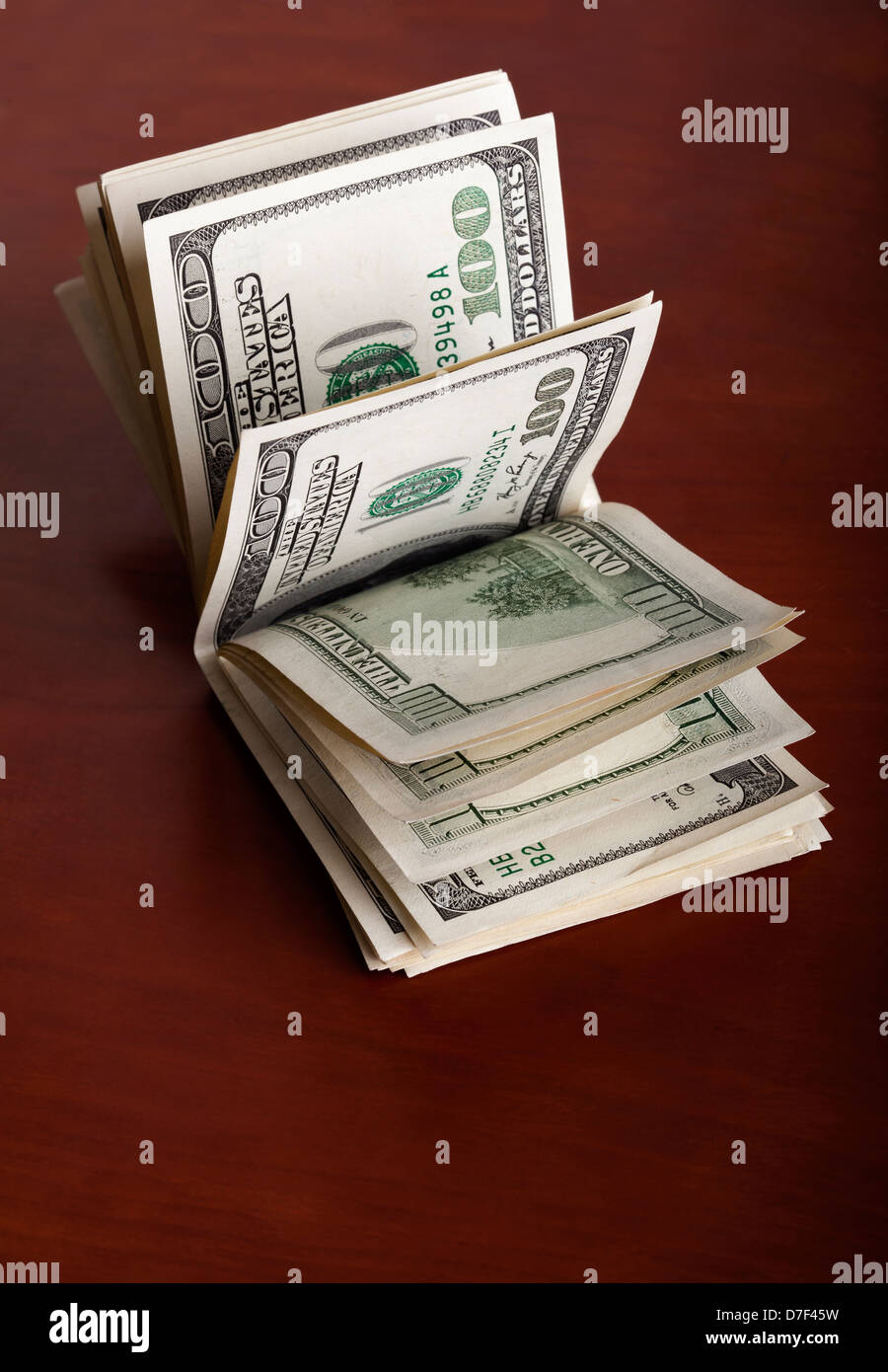 A folded stack of 100 US$ money notes on brown wooden background Stock ...