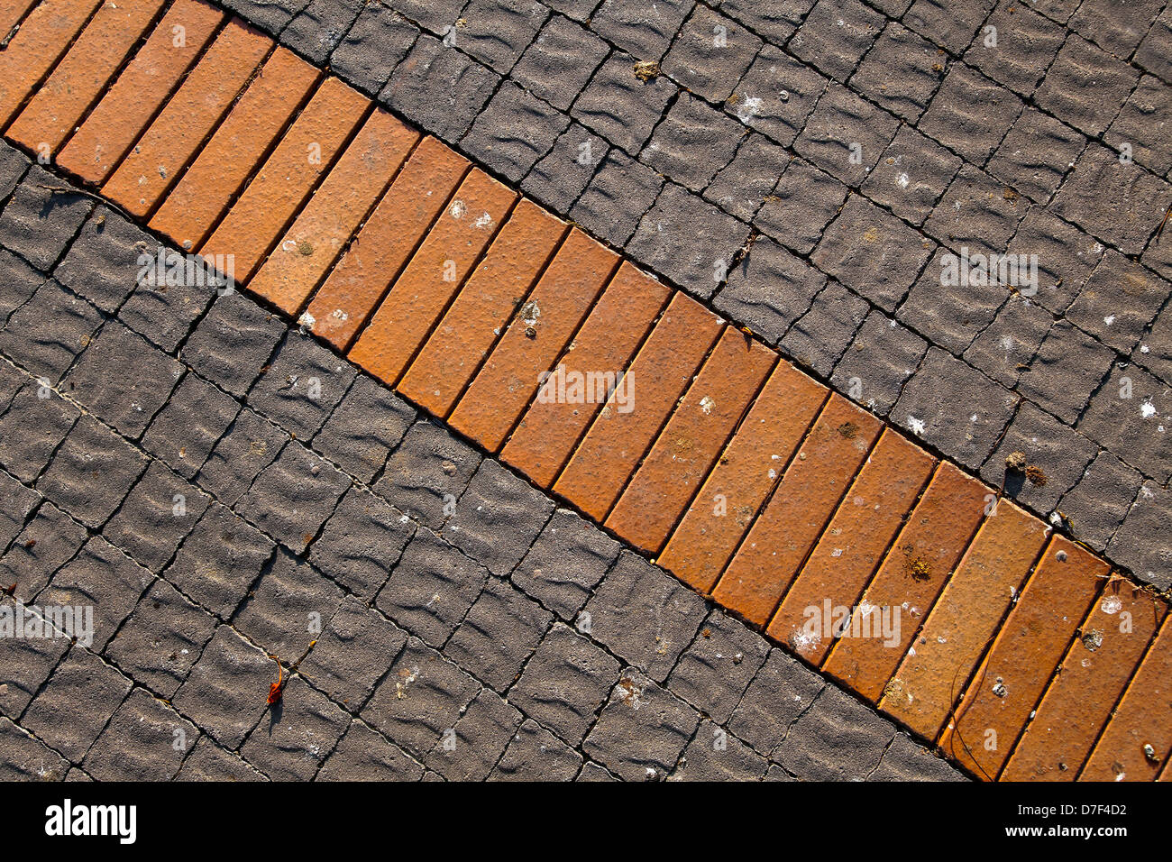 Gray floor tiles with wavy/rippled texture and red bricks lit by direct ...